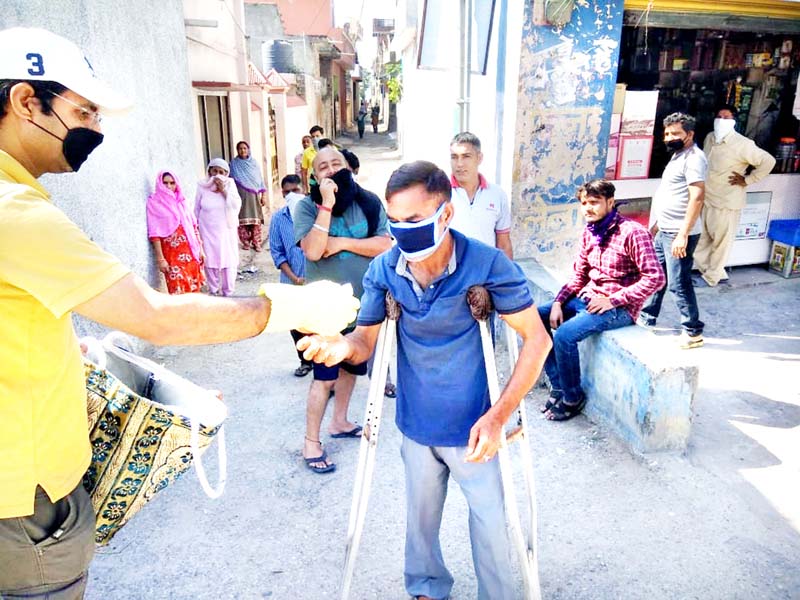 RSS workers provide relief to a handicapped person in Jammu on Sunday ...